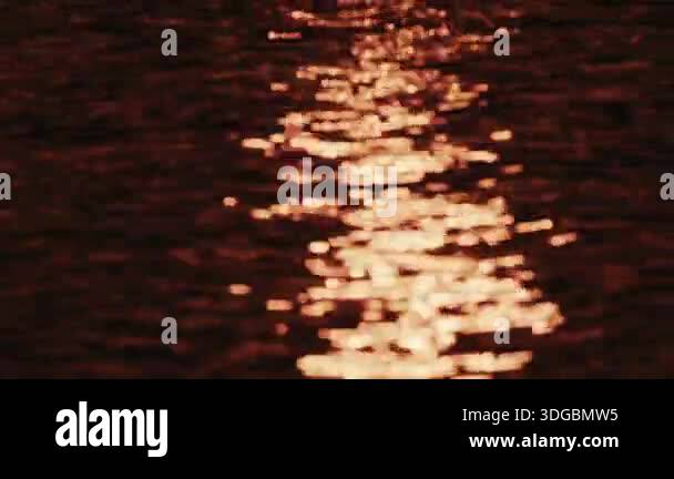 Close up of orange and gold sunset reflections moving across gentle ...