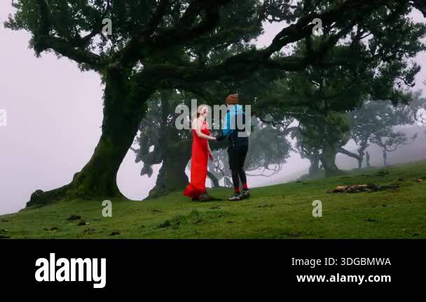 couple dancing under oak tree, red dress sweeping across misty hillside ...