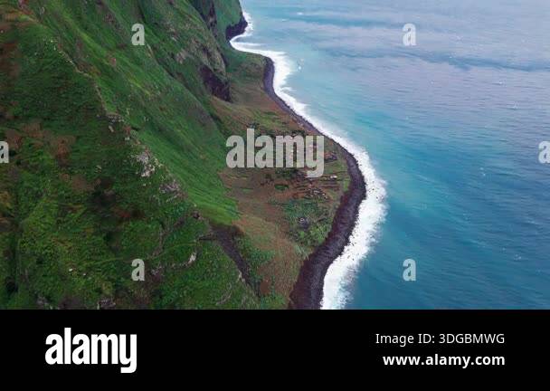 aerial curved coastline with foamy surf emerald water hugging rugged ...