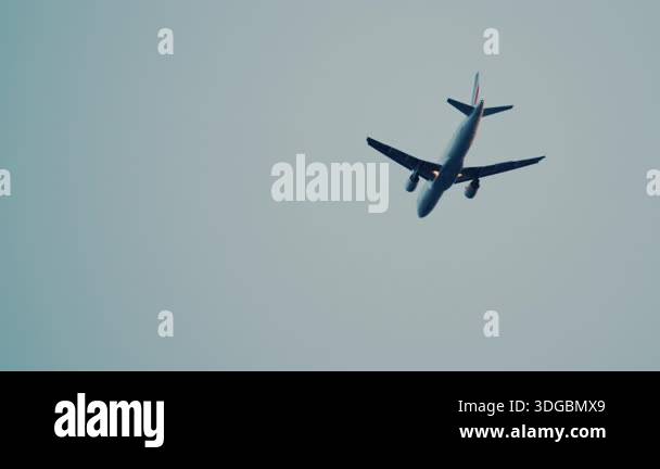 Commercial airplane flying overhead against a clear blue sky, captured ...
