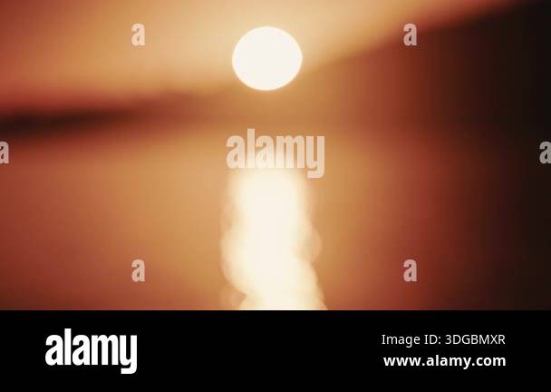 Wide shot of the sunset illuminating the sea surface, creating a bright ...