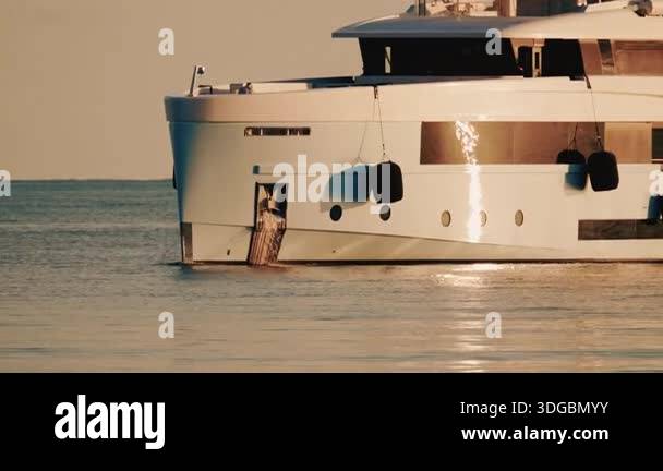 Side view of a modern luxury yacht moving across calm sea water with a ...