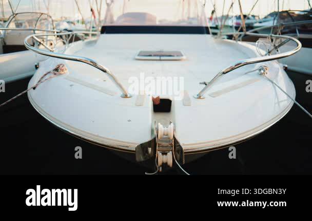 Front view of a white motorboat bow secured to the dock, showing metal ...