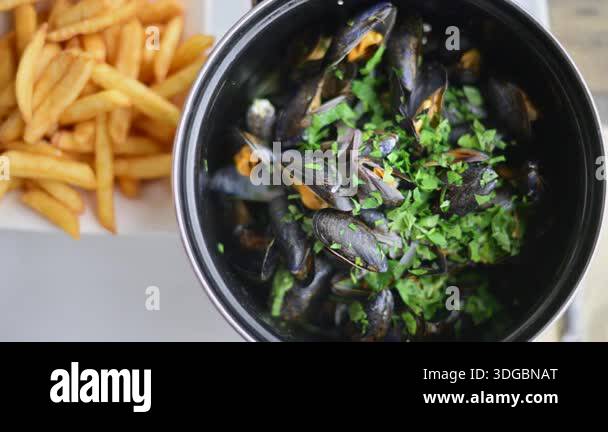 Cooked mussels served in a pot with herbs and sauce, accompanied by ...