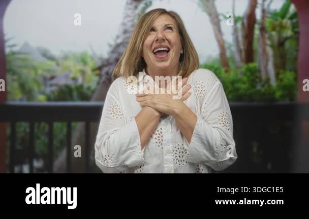 Woman claps hands in green forest setting wearing white blouse and ...