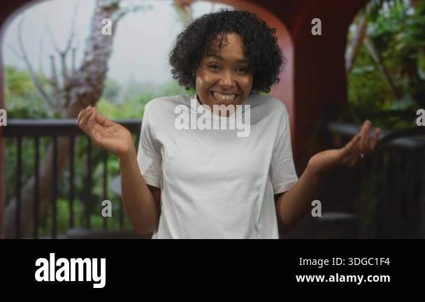 Woman face shrug with raised hands and broad grin in indoor hotel ...