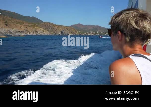 Tourist observing the coastline and a small boat from a ferry near ...