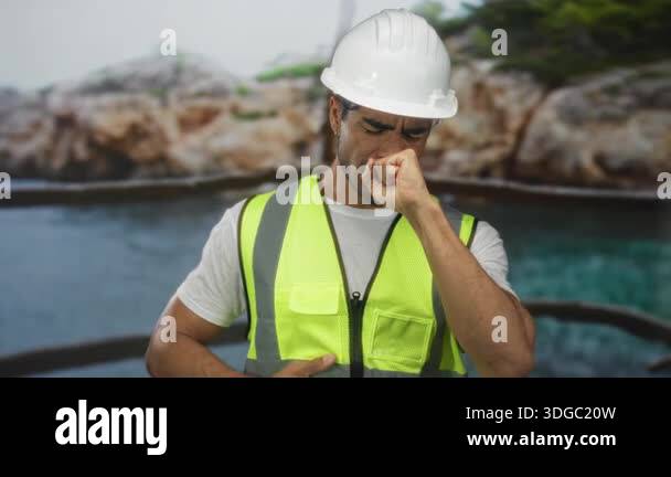 Man coughing into fist while holding chest on beach beside rocky shore ...