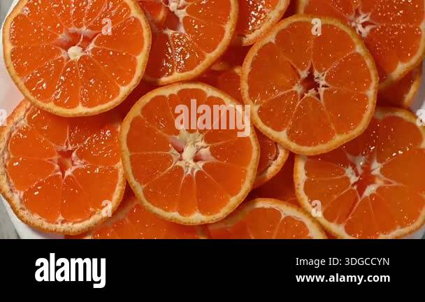 A seamless 4K video loop of fresh mandarin slices rotating smoothly on ...