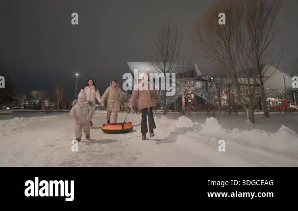 ALMATY, KAZAKHSTAN - DECEMBER 07 2025: Family walks across snowy park ...