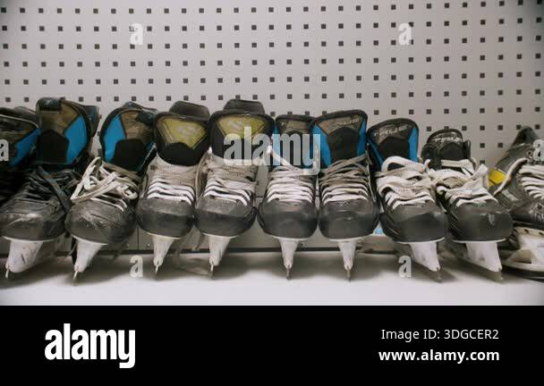 Ice hockey skates rest in neat row on pegboard rack. Prepared equipment ...