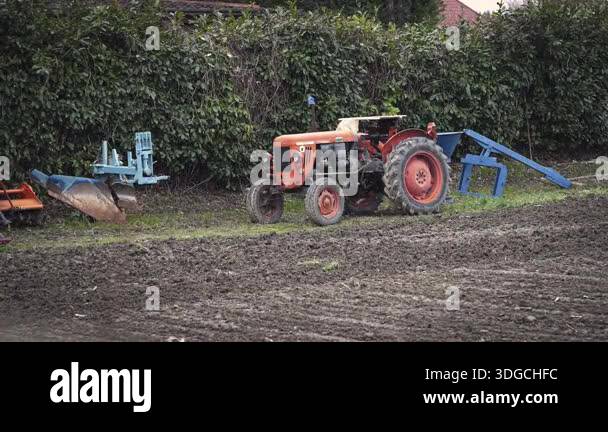 Old orange tractor with various agricultural implements parked on a ...