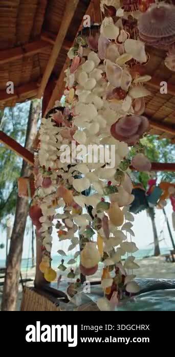Vertical view of hanging seashell wind chimes inside a wooden beach hut ...