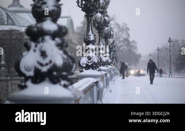 Pedestrians walk across the snow-covered Pont Alexandre III in Paris ...