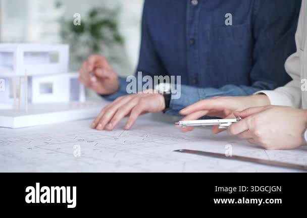 Architects collaborating over blueprints and laptop, pointing to ...