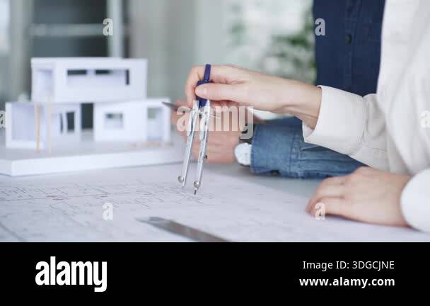 Architects collaborating over blueprints and laptop, pointing to ...