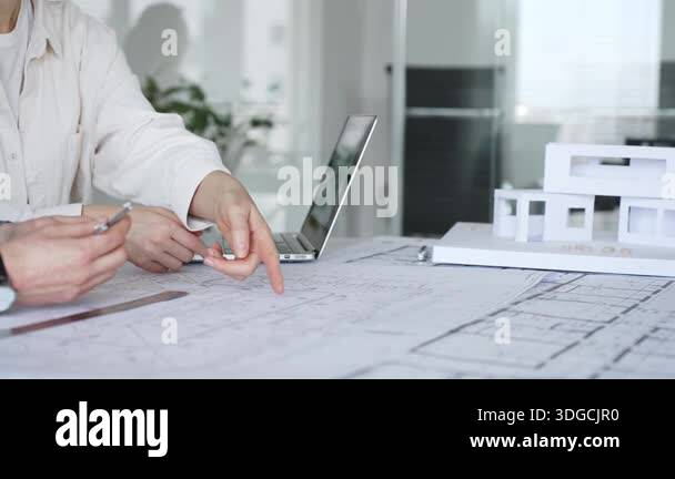 Architects collaborating on building design, discussing blueprints and ...