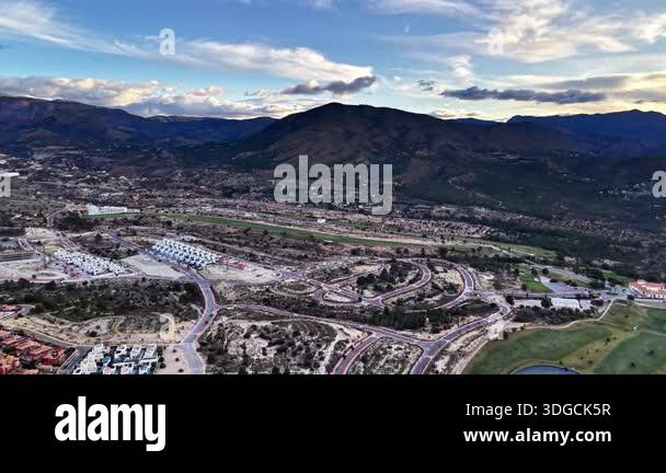 evening suburb nestled in valley with winding highways and golf course ...