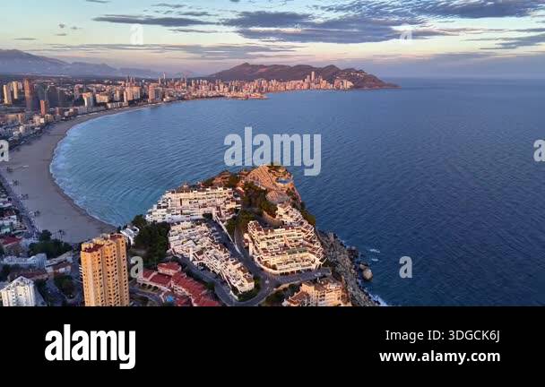 aerial cliffside headland overlooking curved bay at dusk orange light ...