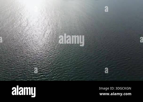 Aerial video of calm sea surface with gentle ripples and sunlight ...