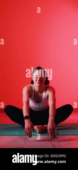 A girl performs a butterfly stretching yoga exercise in a vertical 4K ...