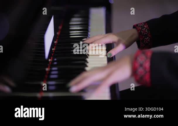 Close-up of a womans hands playing a black grand piano. The pianists ...