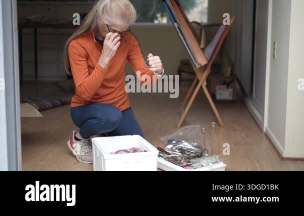 Mature woman looks closely at silver cutlery serving pieces and recalls ...