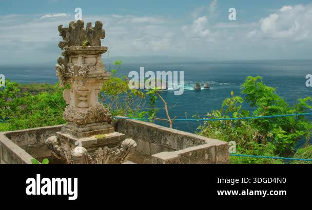 Stone hindu shrine stands on cliff edge overlooking blue ocean at Nusa ...