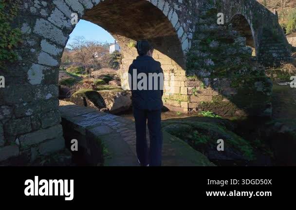 Female pilgrim walking in slow motion under a beautiful medieval stone ...