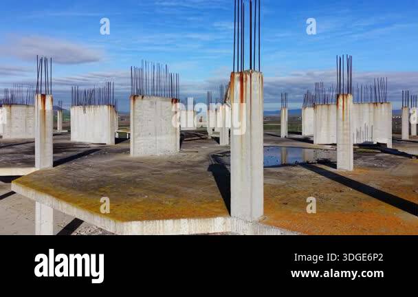 Unfinished rooftop with vertical concrete pillars and exposed steel ...