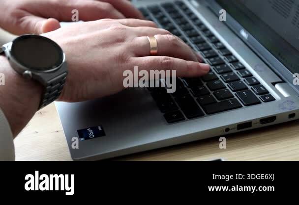 A close up slow motion video of male hands typing on laptop keyboard ...