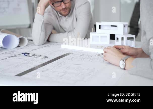 Architecture professionals collaborate over blueprints and a house ...