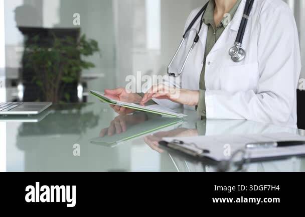 Doctor in white coat with stethoscope using tablet at office desk ...