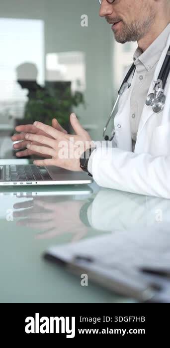 Doctor wearing a lab coat and stethoscope, typing on a modern laptop at ...