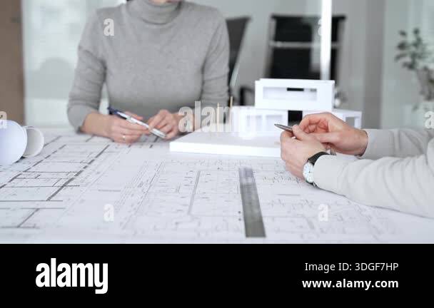 Architects collaborating on building project, discussing blueprints and ...