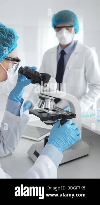 Two scientists in lab coats, face masks, and protective glasses ...