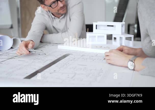 Architecture professionals collaborate over blueprints and a house ...