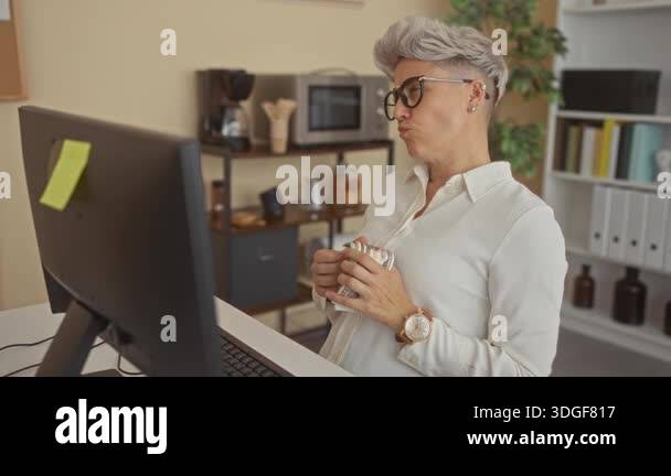Shorthaired woman wearing glasses holding cash bundle by computer ...