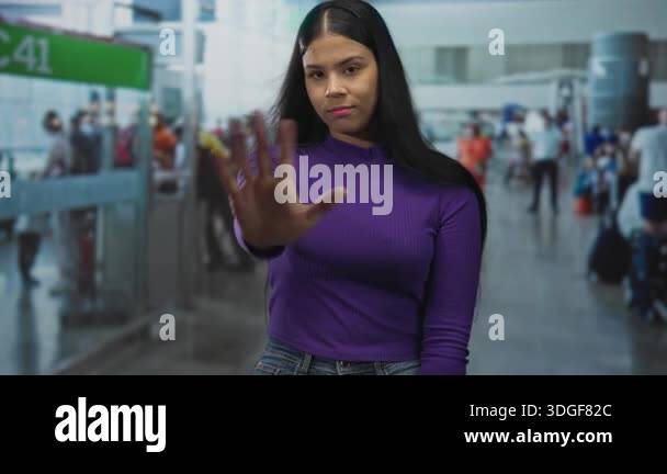 Woman pushing her hand palm forward in a busy airport terminal near ...