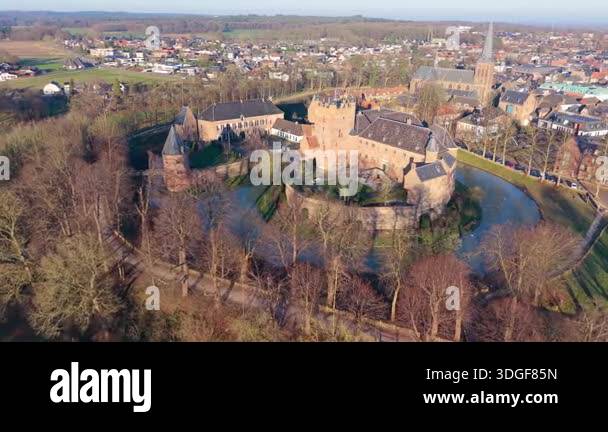 Aerial view of historic castle with moat and towers beside church spire ...