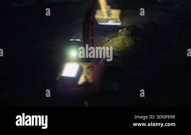 An excavator works the night on a construction site. The industrial ...