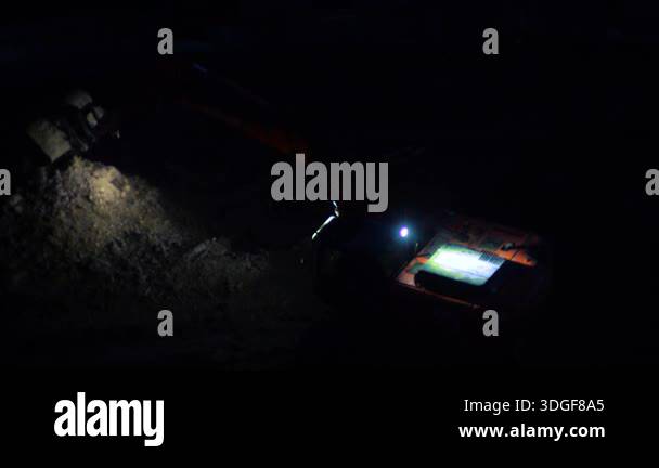 An excavator works the night on a construction site. The industrial ...