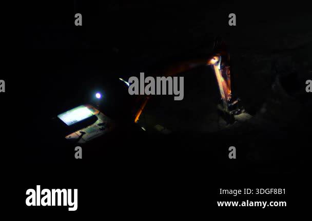 An excavator works the night on a construction site. The industrial ...