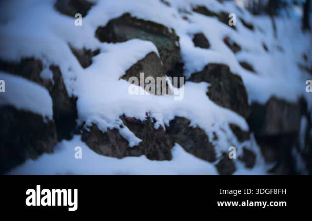 Close-up shot of snow covering stones. A blurred, abstract background ...