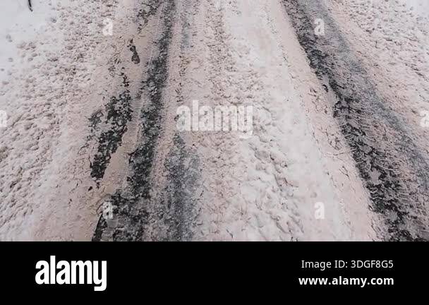 A snow-covered city street after a blizzard, with tire tracks marking ...
