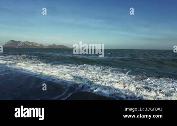 Powerful ocean waves crash against dark concrete shore with distant ...