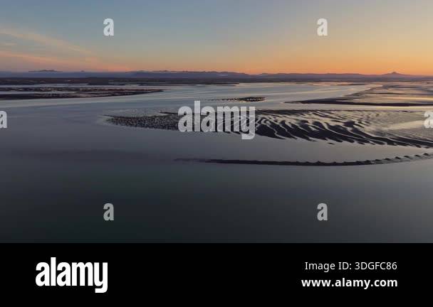 Sunrise at low tide, sun reflecting off black volcanic sand. High ...