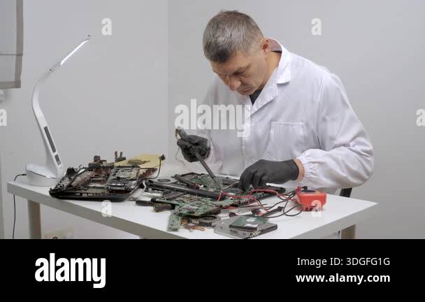 Technician soldering laptop motherboard components during electronic ...