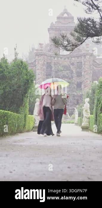 Romantic walk in the rain, a young couple strolls through a parks ...