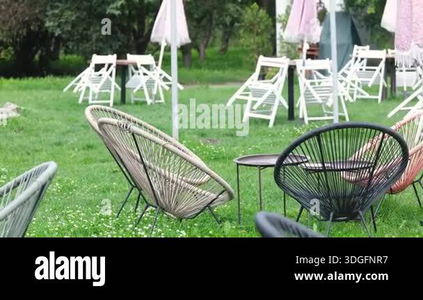 Outdoor seating area with wicker chairs and tables set on green grass ...